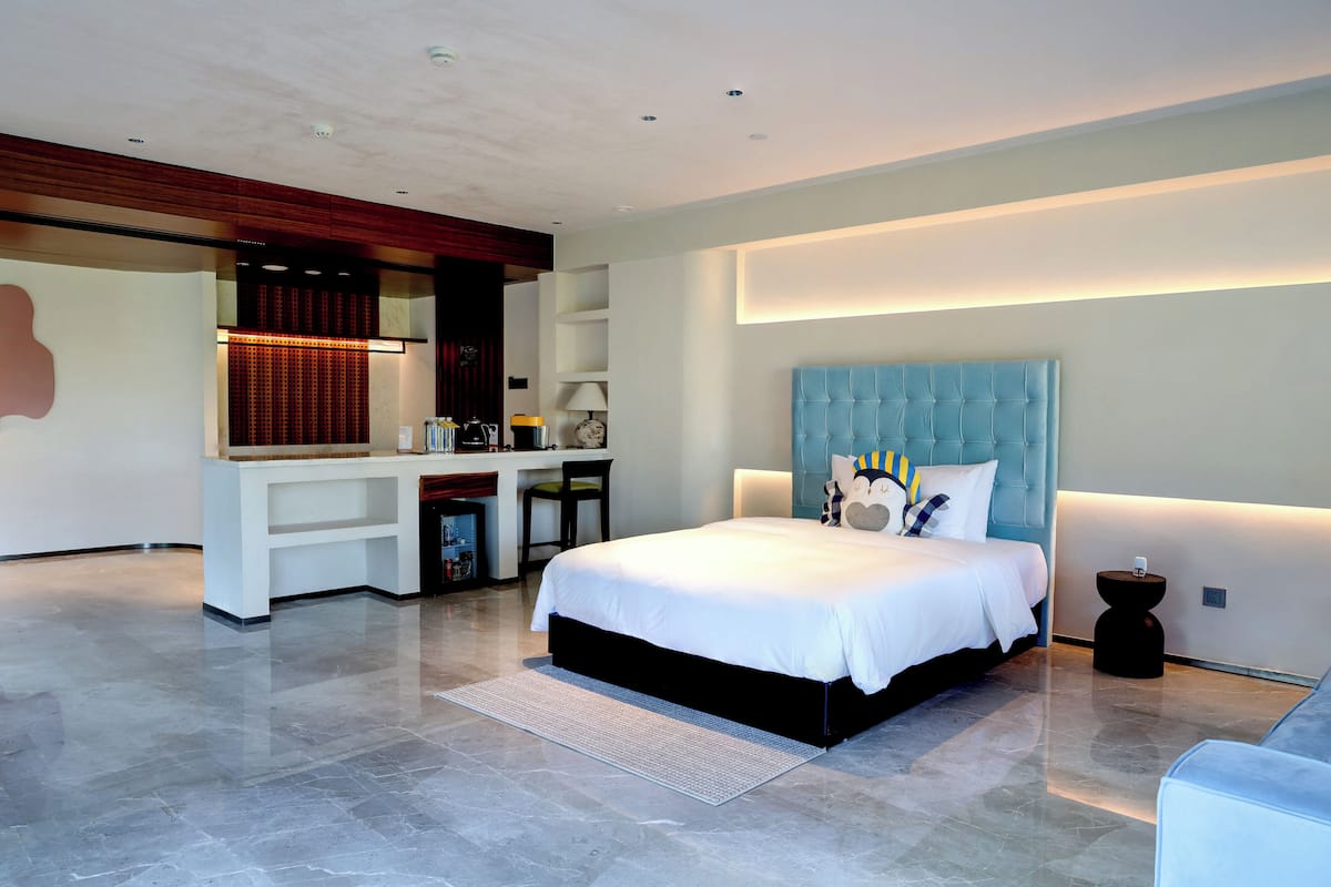 Quarto moderno com cama grande, escrivaninha e área de estar.