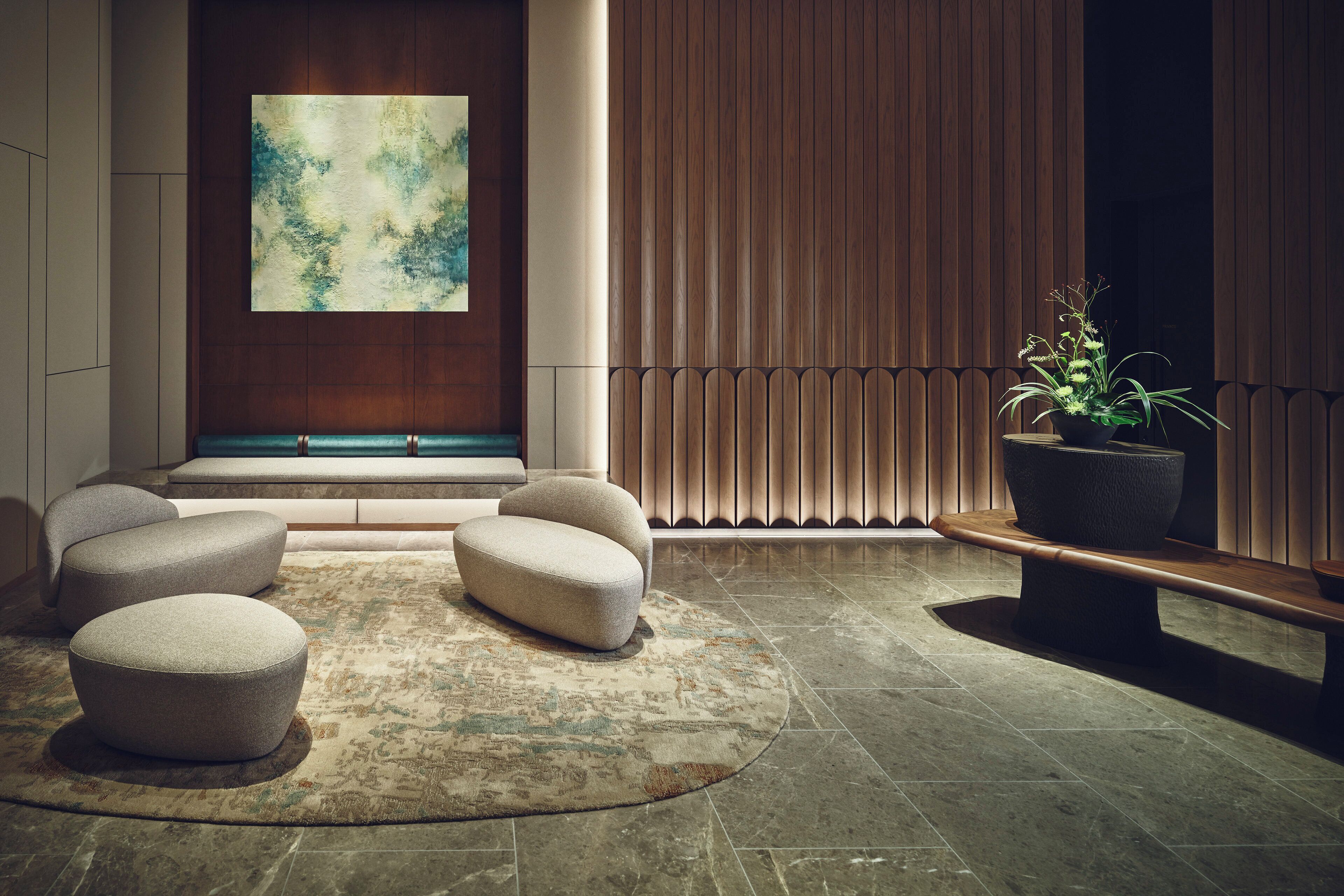 Um lobby moderno com área de estar, uma grande pintura abstrata e uma planta em vaso.