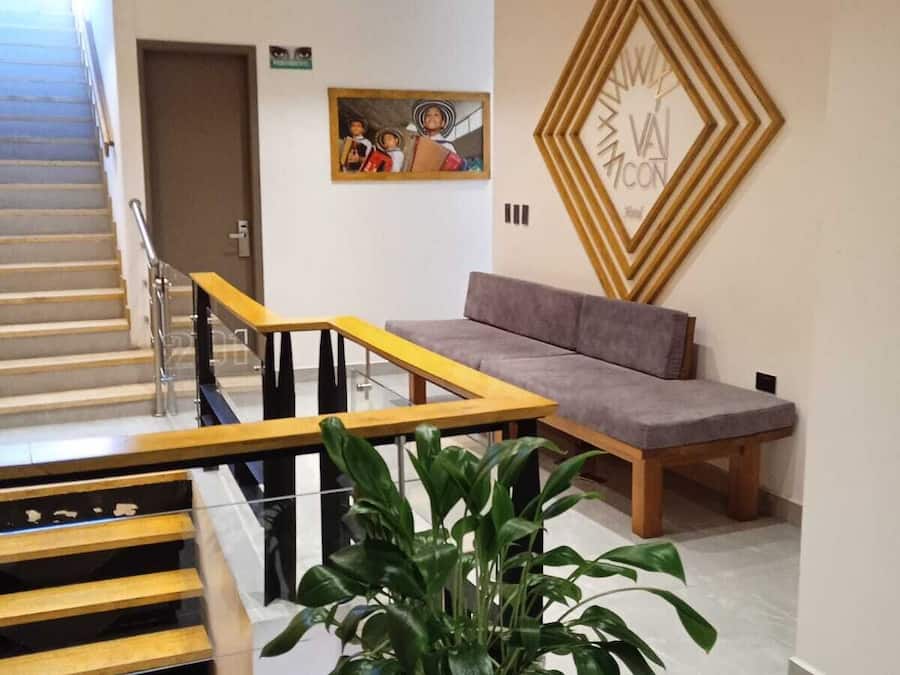 Um hall de hotel moderno com uma escadaria, área de estar e um elemento decorativo na parede.