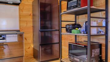 Uma cozinha compacta com geladeira de aço inoxidável, micro-ondas e lava-louças.