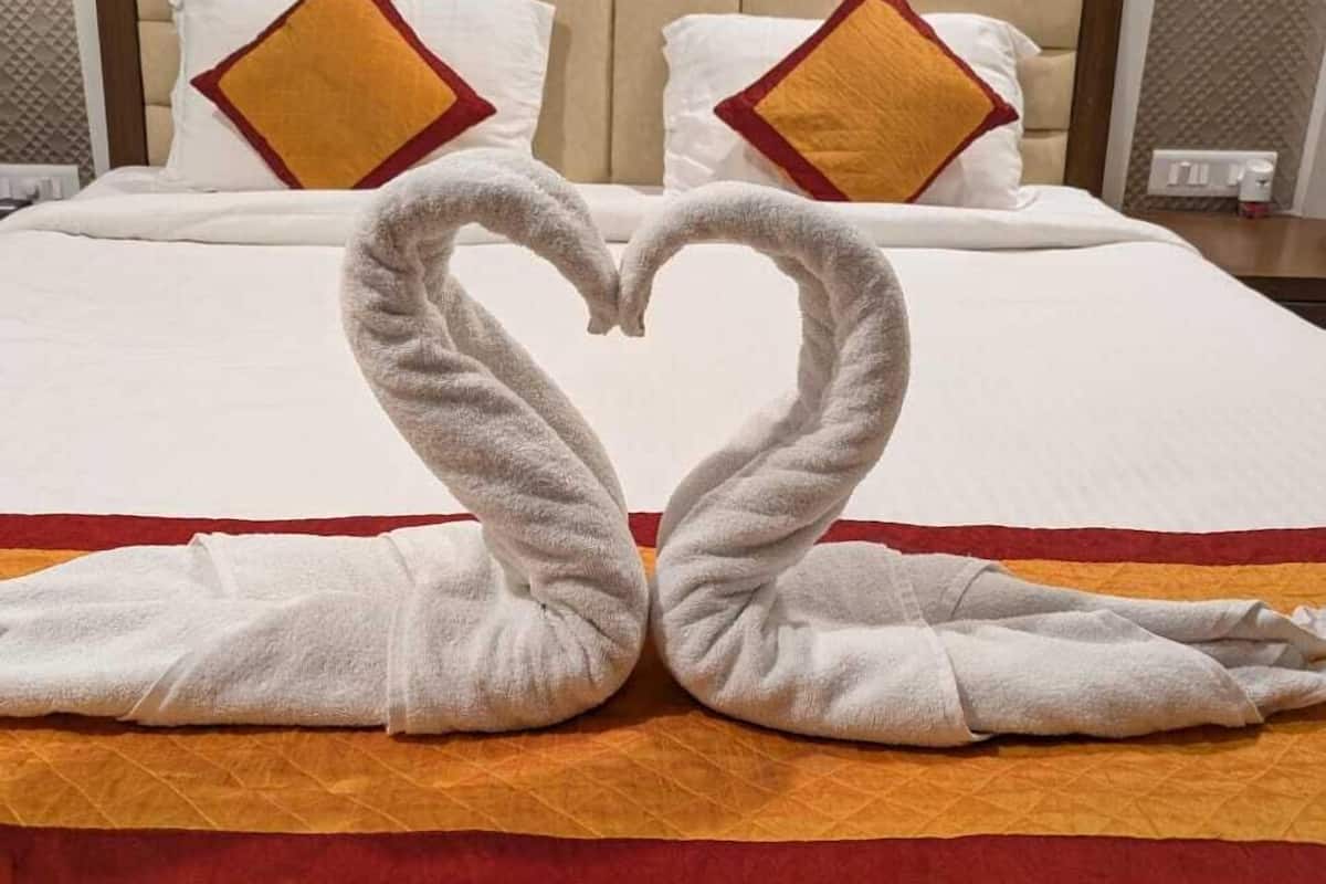 Quarto de hotel com cama e arranjo de toalha em formato de coração.