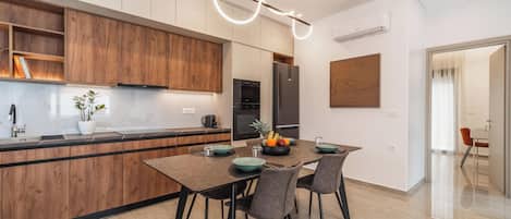Uma cozinha moderna com armários de madeira, bancada de mármore e um espaço de refeições com mesa e cadeiras.
