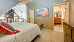 Um quarto com uma cama, uma cômoda de madeira, uma mesinha e um quadro na parede.