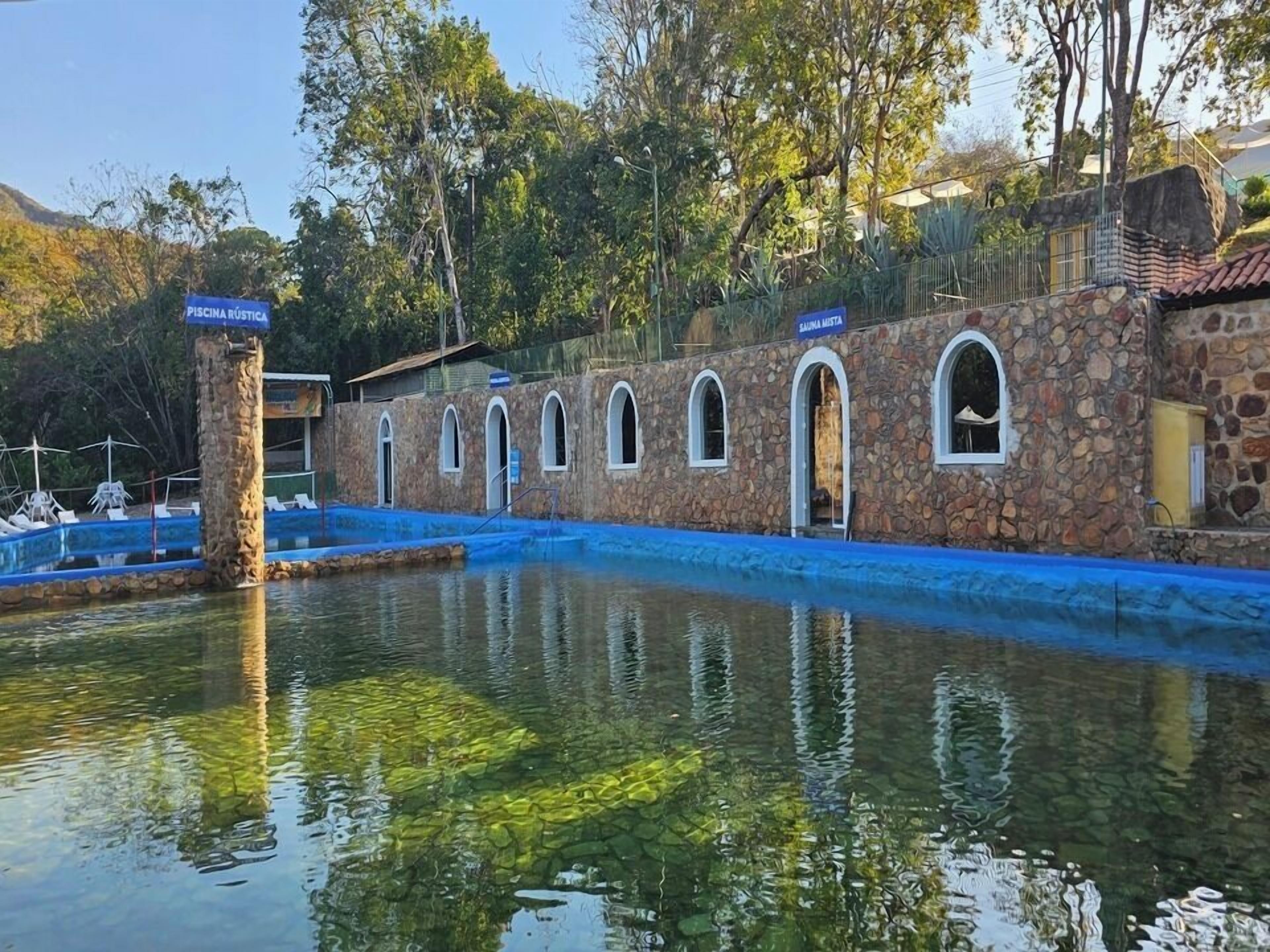 Um edifício de pedra com janelas em arco e uma piscina.
