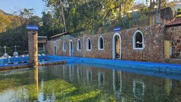 Um edifício de pedra com janelas em arco e uma piscina.
