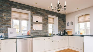 Uma cozinha moderna com armários brancos, painel de backsplash de pedra e lustre.