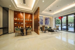 Interior moderno com área de refeições, estantes de livros e vista através de grandes portas de vidro.