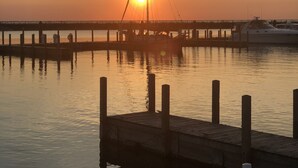 Um cais se estendendo sobre águas calmas, com um pôr do sol ao fundo.