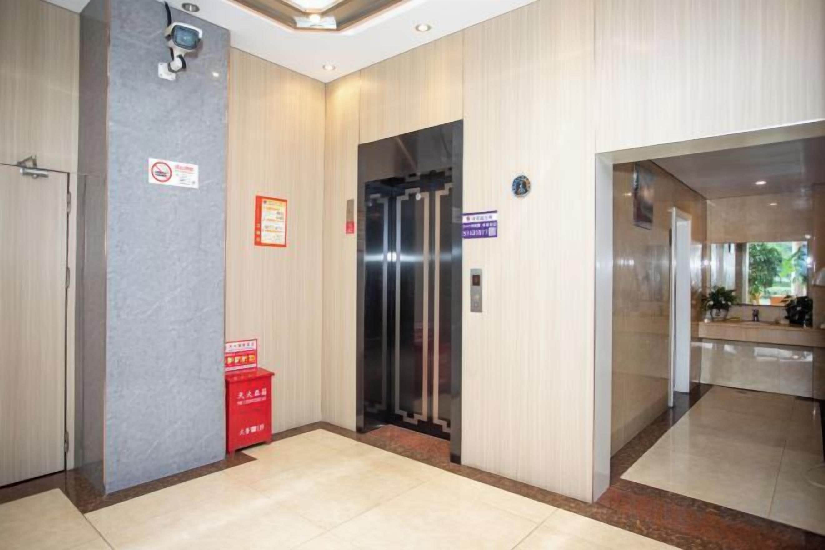 Um saguão de hotel com balcão de recepção, elevador e câmera de segurança instalada na parede.