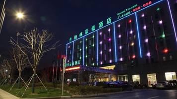Hotel com vários andares, letreiros iluminados e área de estacionamento.