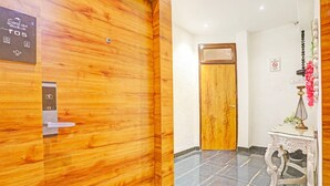 Uma área de recepção de hotel com um balcão de madeira, um sinal indicando a disponibilidade de quartos e uma placa de proibido fumar na parede.