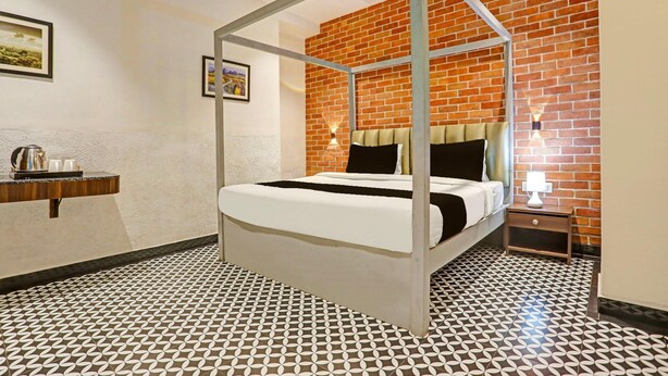 Quarto com cama de dossel, parede de tijolos e chão de azulejos.