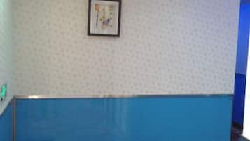 Quarto com parede estampada, quadro emoldurado e divisória azul.