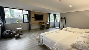 Quarto de hotel moderno com uma cama grande, uma escrivaninha, uma cadeira e uma televisão.