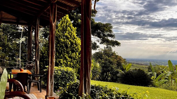 Uma área de estar coberta ao ar livre com vista para uma paisagem exuberante.