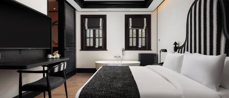 Quarto de hotel moderno com uma cama grande, uma escrivaninha e uma televisão.