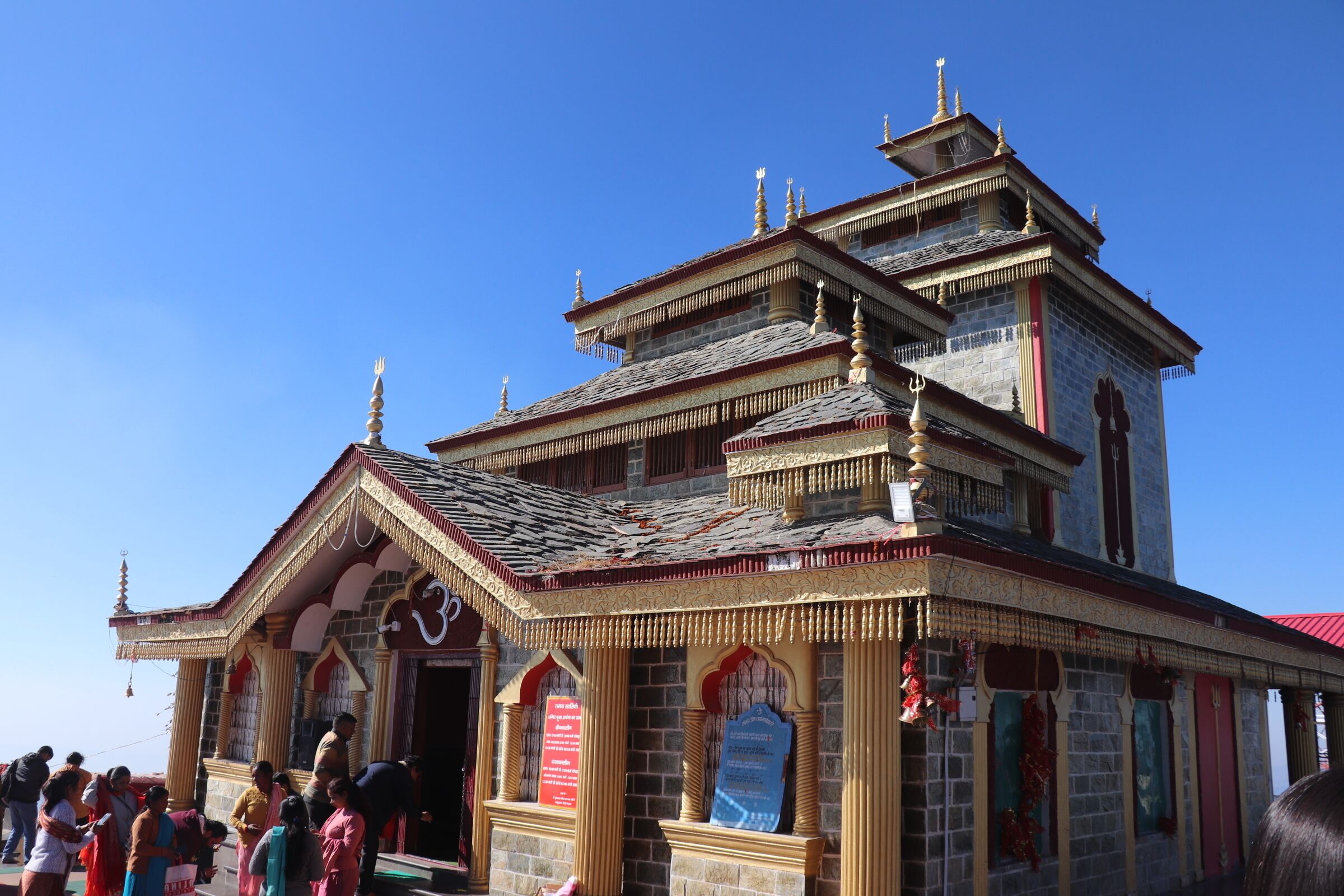 Um templo com vários níveis e uma torre central imponente, rodeado por visitantes.