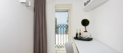 Quarto de hotel moderno com varanda, área de refeições e vista para o mar.