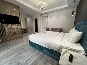 Quarto moderno com cama grande, televisão e guarda-roupa.