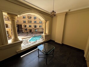 Varanda com mesa de vidro e vista para um pátio com colunas e piscina.