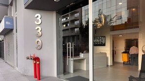 Um edifício moderno com o número 339 na fachada, um extintor de incêndio e uma entrada de vidro que dá para uma área de recepção.