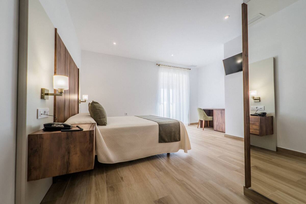 Quarto moderno com cama, mesa de cabeceira e escrivaninha com cadeira.