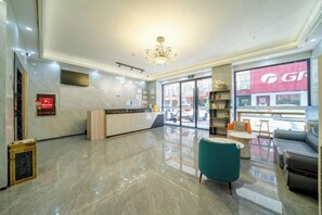 Um saguão de hotel com balcão de recepção, área de estar e uma grande janela com vista.