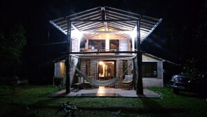 Uma casa de dois andares com varanda coberta e rede.