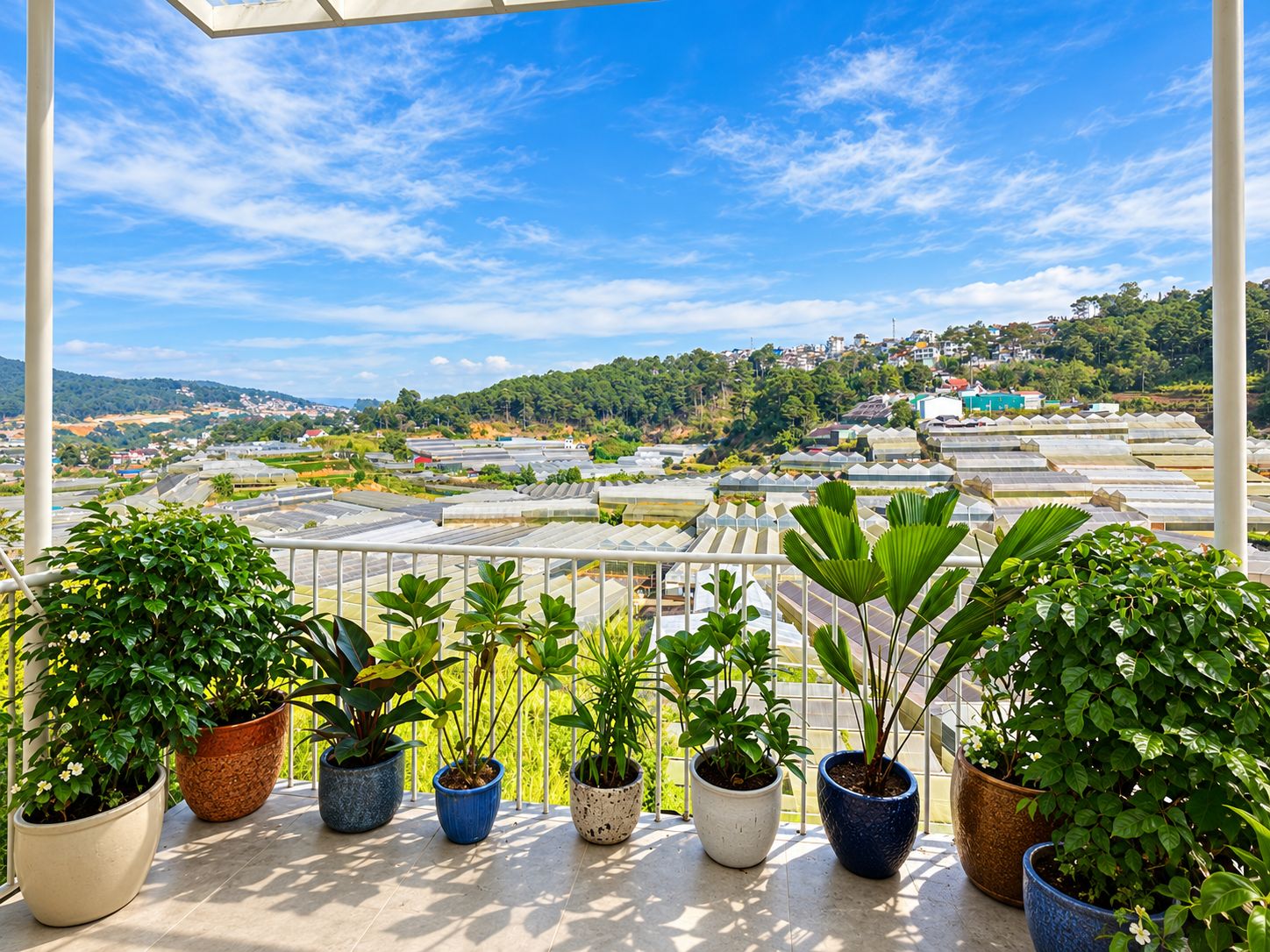 Varanda com vasos de plantas e vista para uma área de estufas.