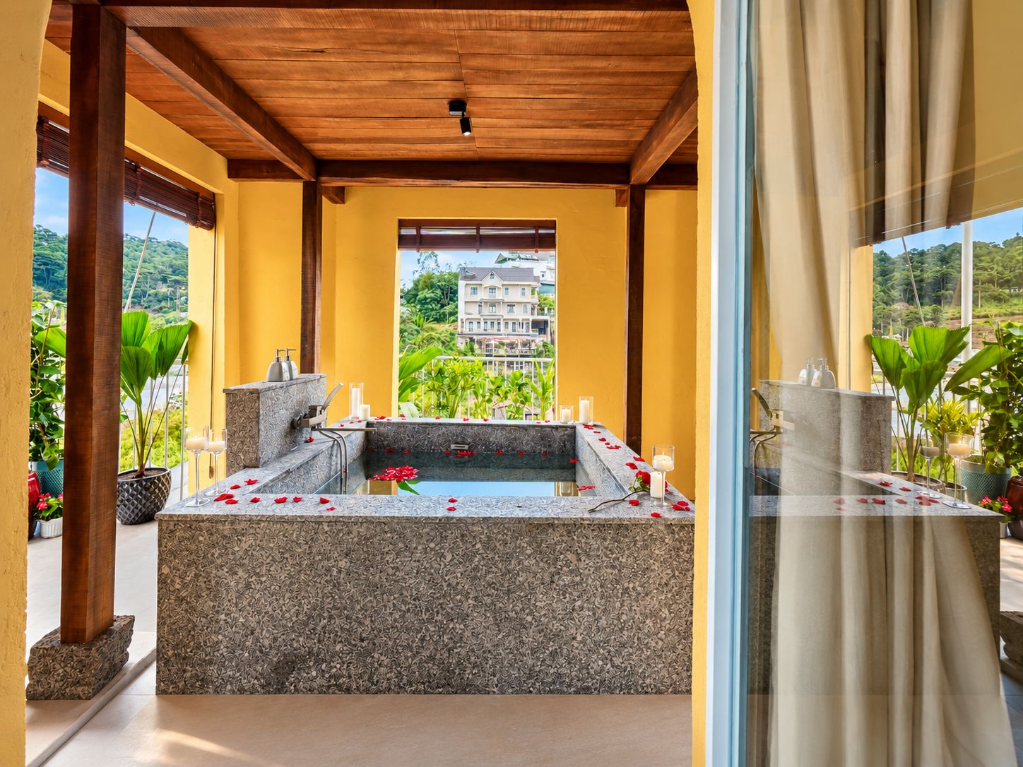 Uma área de spa com uma banheira de pedra, uma pequena piscina e vista para um edifício ao fundo.