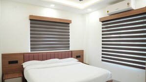 Um quarto moderno com cama, mesas de cabeceira e uma janela com persianas.
