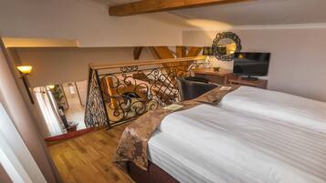 Quarto com cama grande, televisão, escrivaninha e escada.