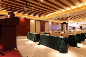 Uma sala de conferências com mesas montadas para uma reunião, um pódio e uma tela grande na frente.