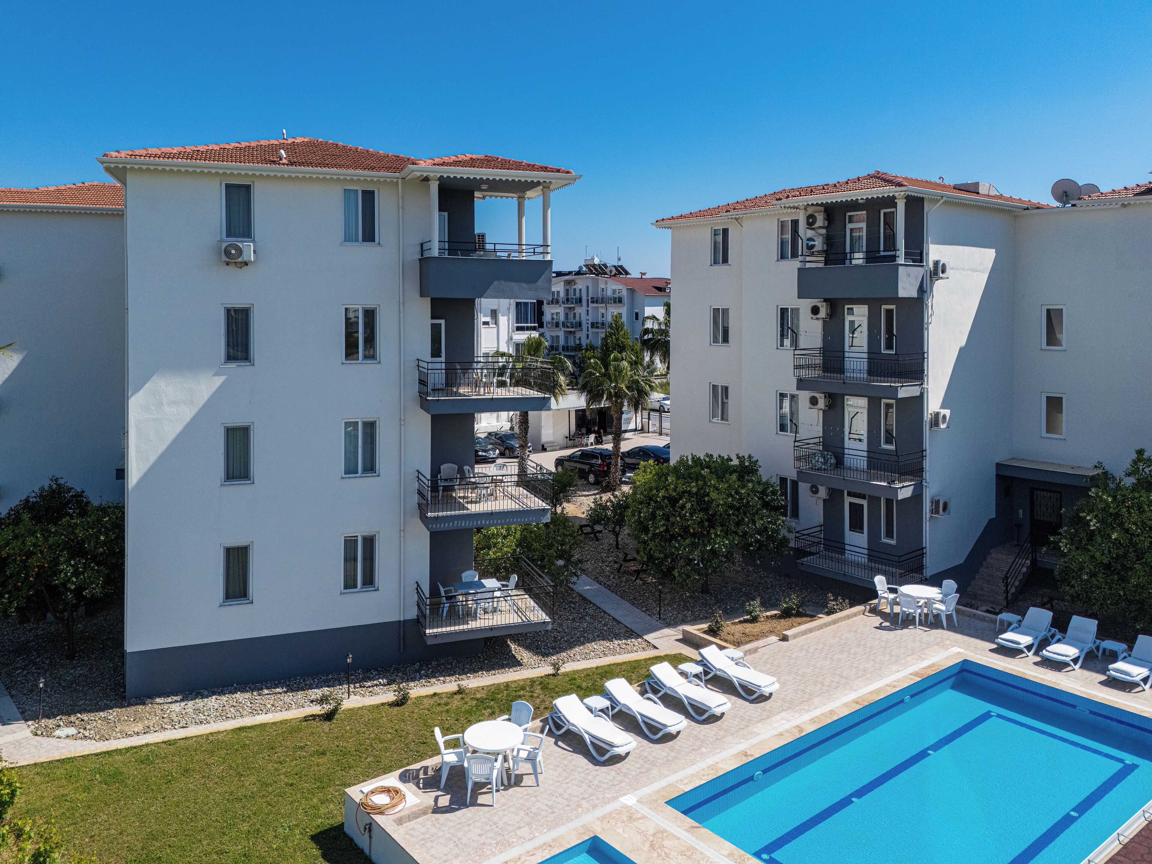 Um hotel com vários andares, varandas, piscina e área externa para sentar.