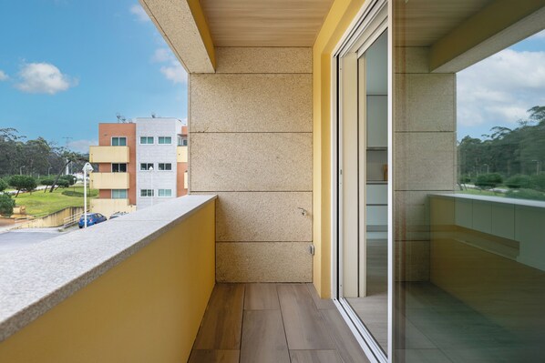Uma varanda com vista para um edifício moderno e céu claro.