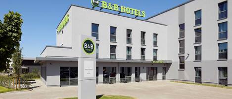 Um hotel de acomodação com design moderno, apresentando uma entrada ampla e área de estacionamento.
