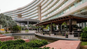 Um hotel moderno com fachada curva, áreas de estar ao ar livre e um elemento central de água.