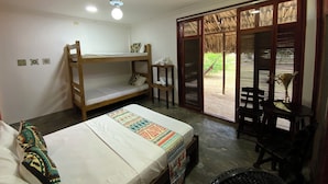 Quarto com cama de solteiro, escrivaninha, cadeira e vista para o exterior.