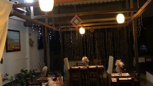 Espaço de refeições interno com mesas e cadeiras de madeira, decorado com jogos americanos e centros de mesa com folhas de outono.