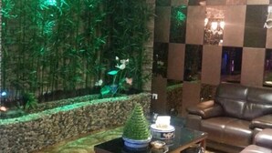 Sala de estar com sofá de couro, uma mesa decorativa e parede com vegetação vertical.