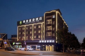 Hotel com vários andares, letreiros iluminados, restaurante no térreo e estacionamento.