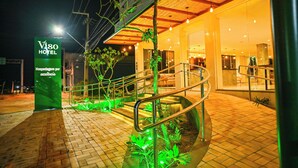 Vista noturna da entrada do Hotel Viso, com design moderno, incluindo uma escadaria e uma placa.