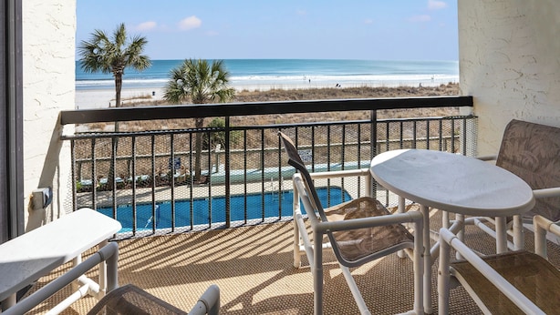 Varanda com vista para a praia e piscina.