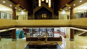 Um hall amplo com um elemento central de água, vários níveis com guarda-corpos de vidro e um design de teto moderno.