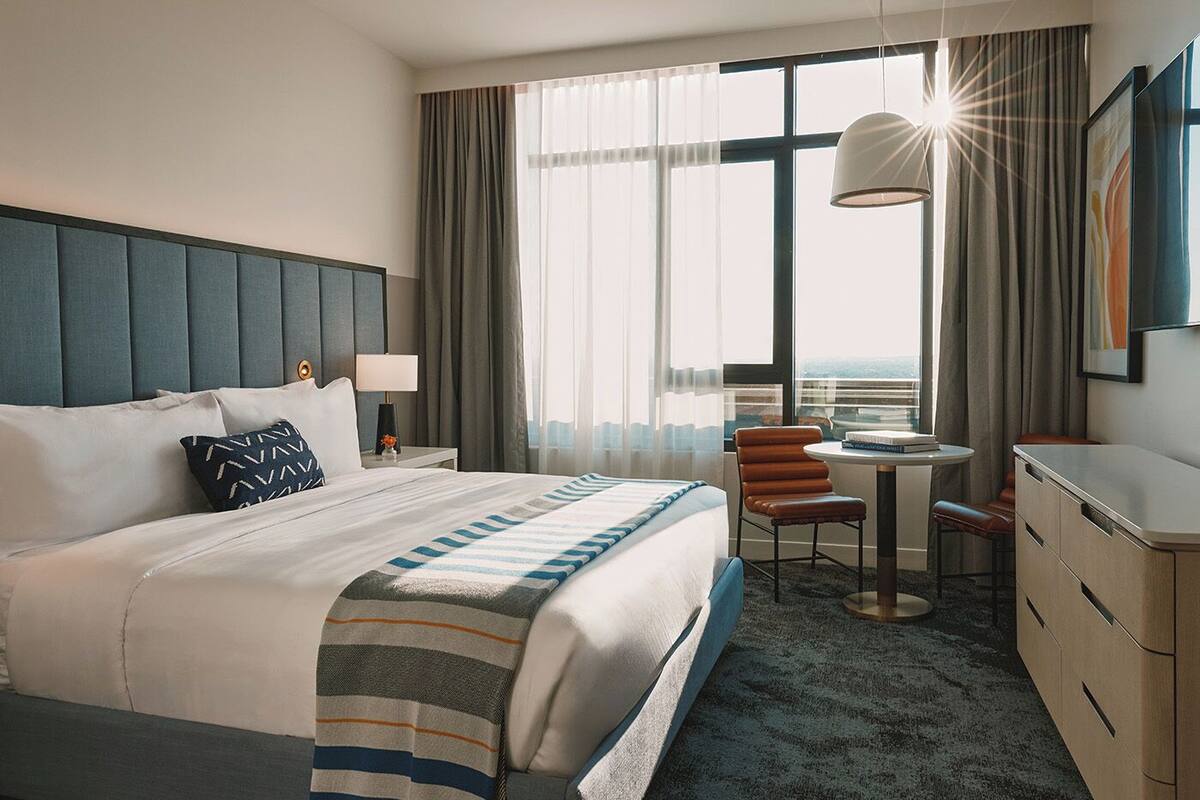 Quarto de hotel com uma cama grande, uma escrivaninha e vista para a cidade.