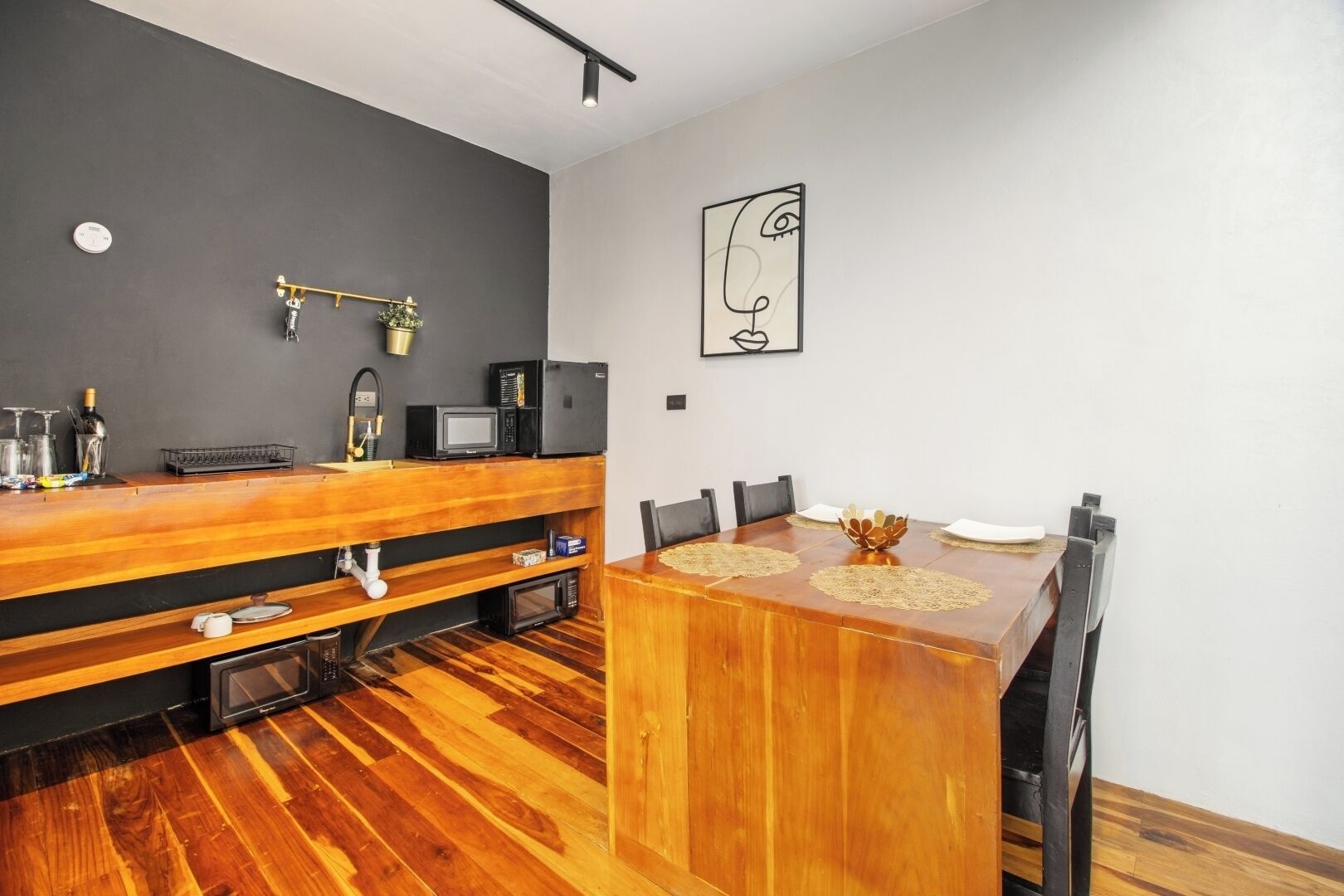 Uma cozinha compacta com bancada de madeira, micro-ondas, torradeira e máquina de café.