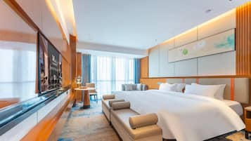 Quarto de hotel moderno com uma cama grande, um sofá, uma televisão e vista para a cidade.