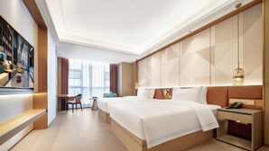 Quarto de hotel moderno com uma cama grande, uma escrivaninha e um espaço de estar com vista para a cidade.