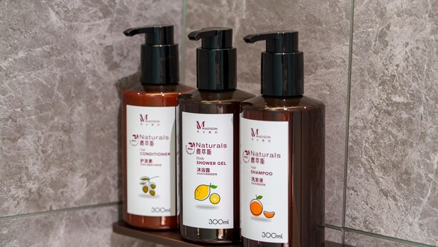 Três frascos de produtos para cabelo em uma prateleira.