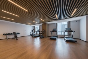 Uma academia ampla com esteiras, elípticos e um banco de musculação.